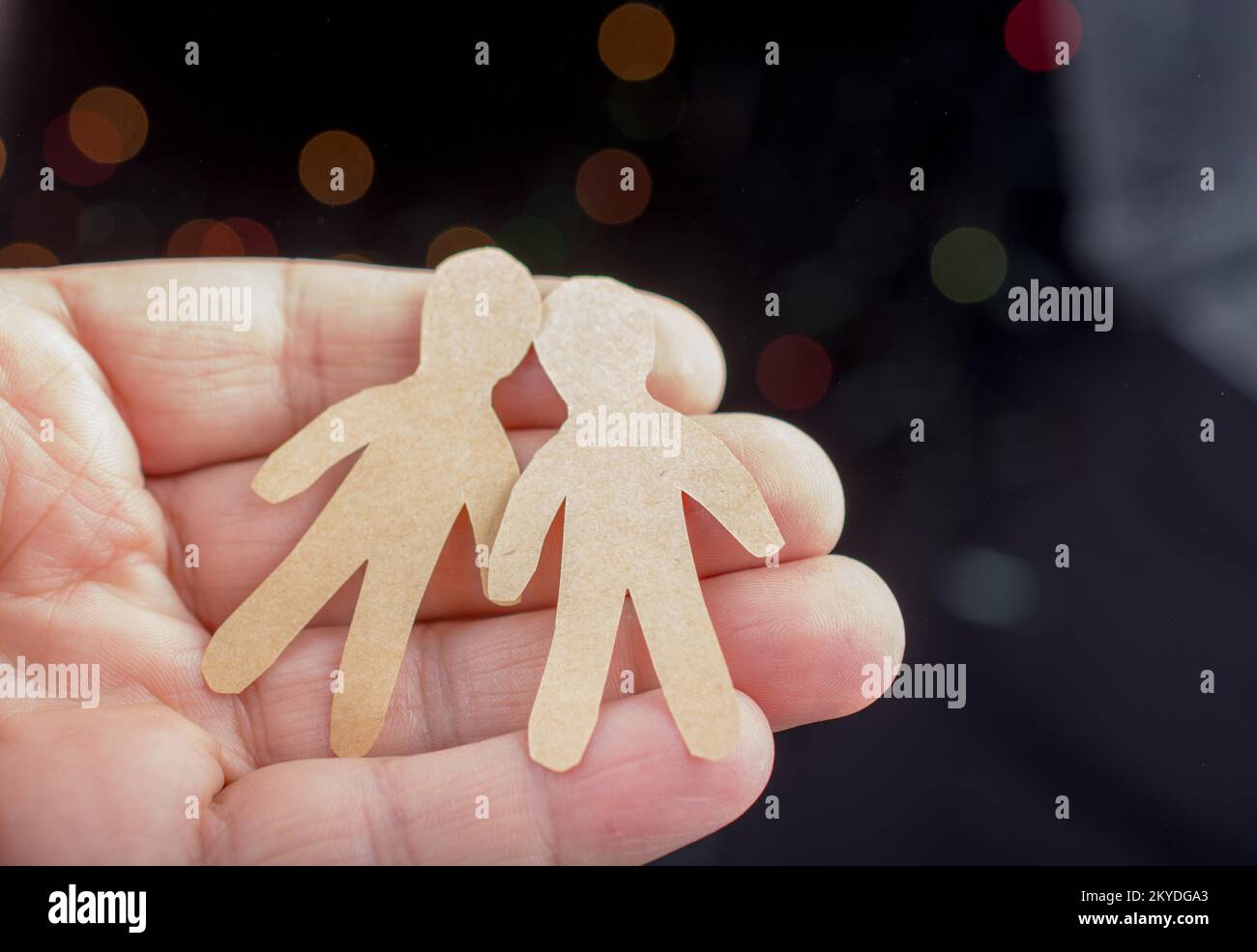 Paper man shape in hand on bokeh light background Stock Photo - Alamy