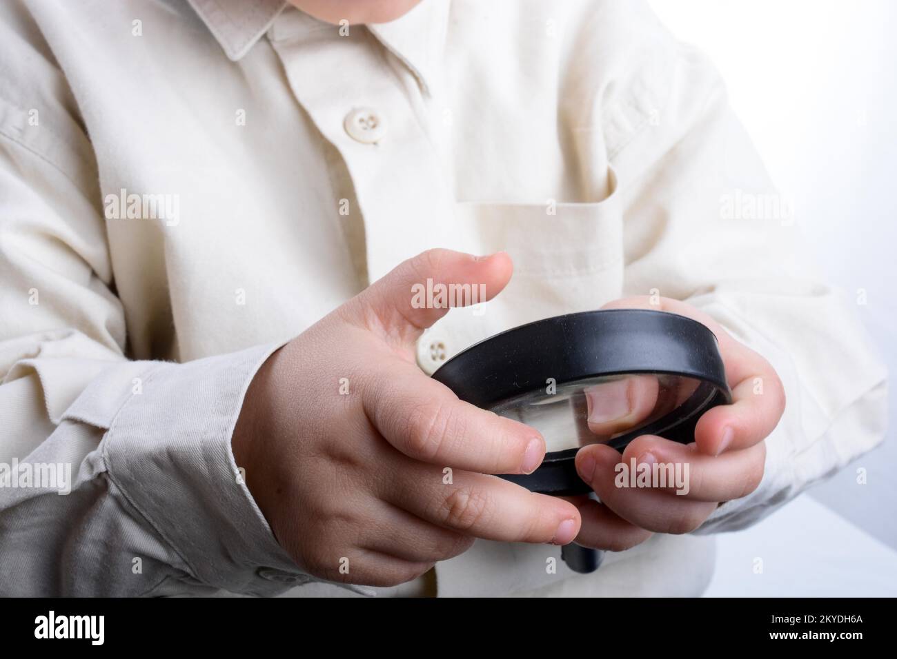 Baby holding a magnifying glass in hand on a white background Stock ...
