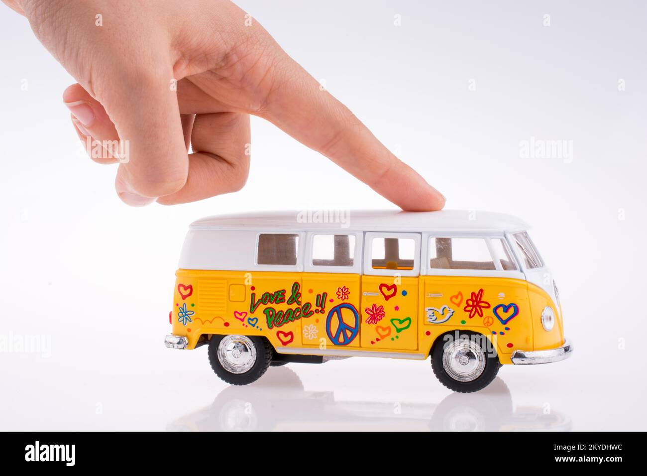 Hand holding a yellow Peace Van on a white background Stock Photo - Alamy