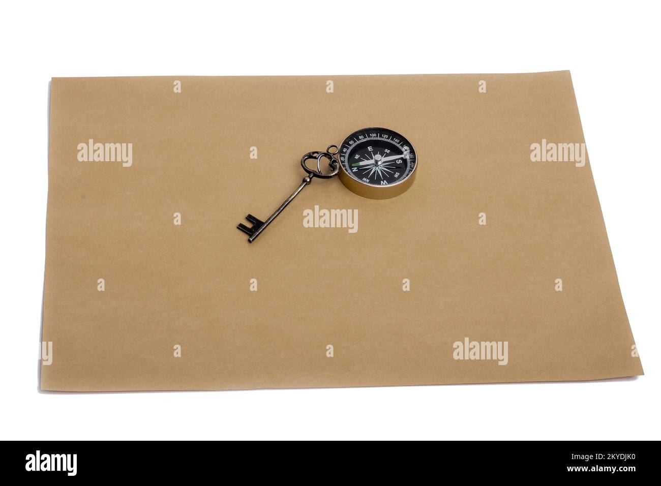 Key and compass on a sheet of colored plain paper with a white ...