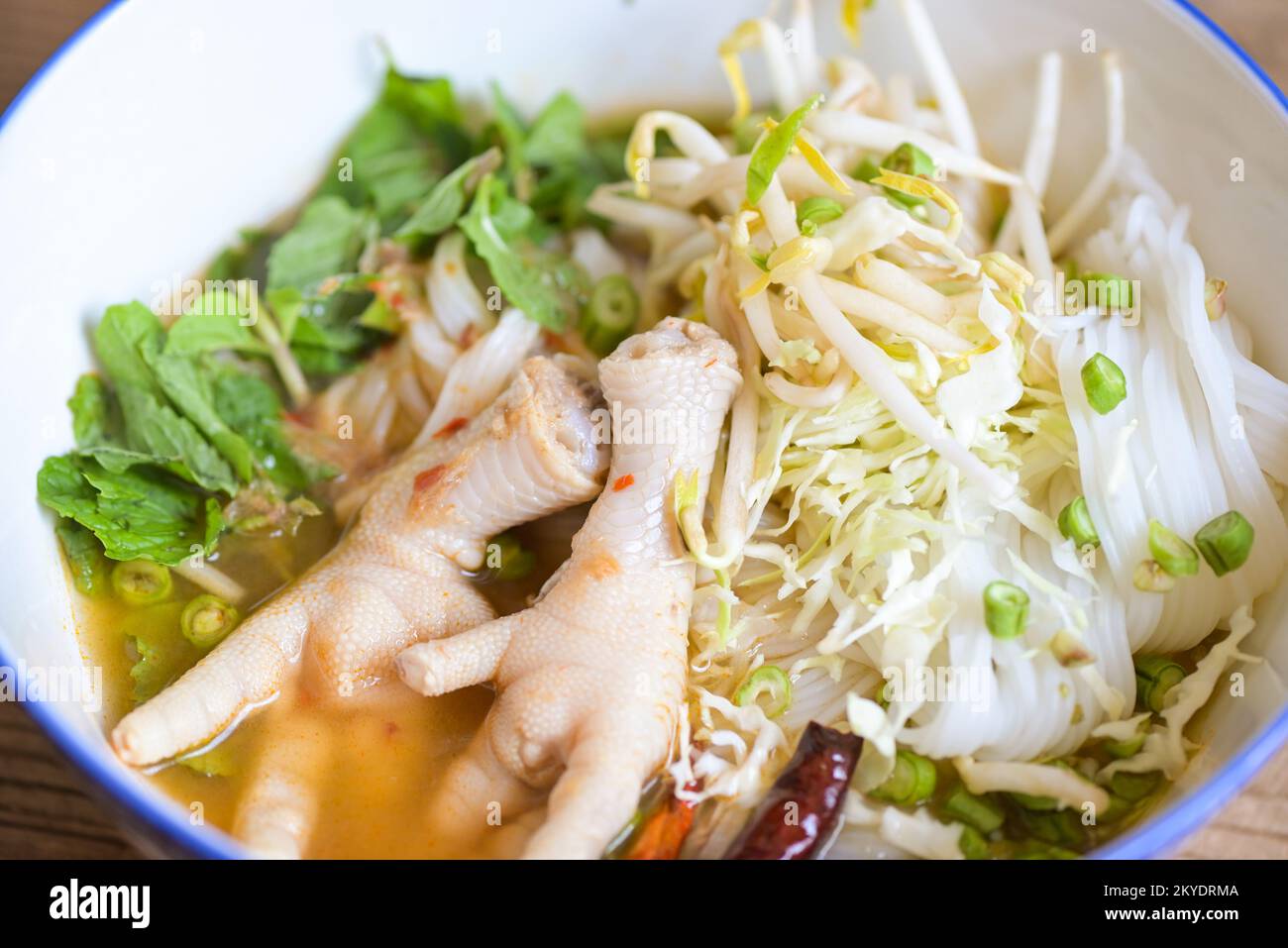 Rice noodles with chicken feet on soup bowl on wooden table food ...