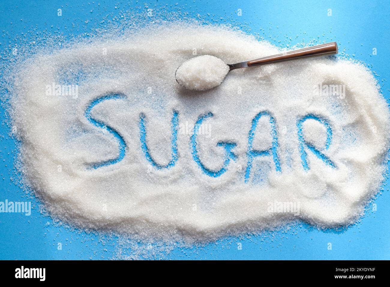 Sugar on spoon and blue background, white sugar for food and sweets ...