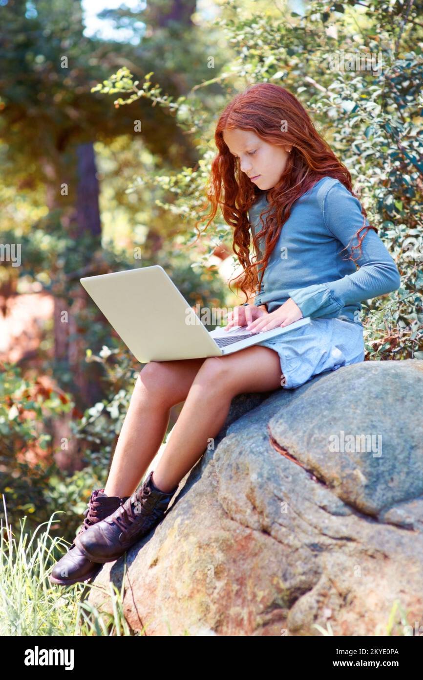 Missing out on a great adventure. A young girl working on her laptop ...