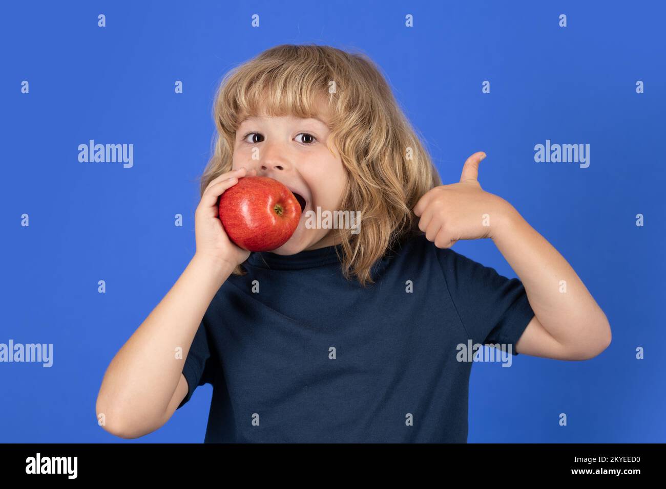 Red apple. Little boy biting apple with fynny face. Kid eats healthy ...