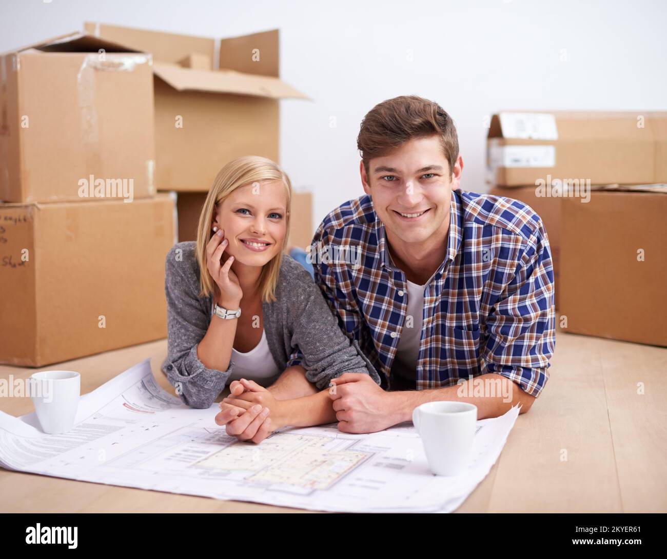 Deciding on the layout of their new flat. A young couple lying on the ...