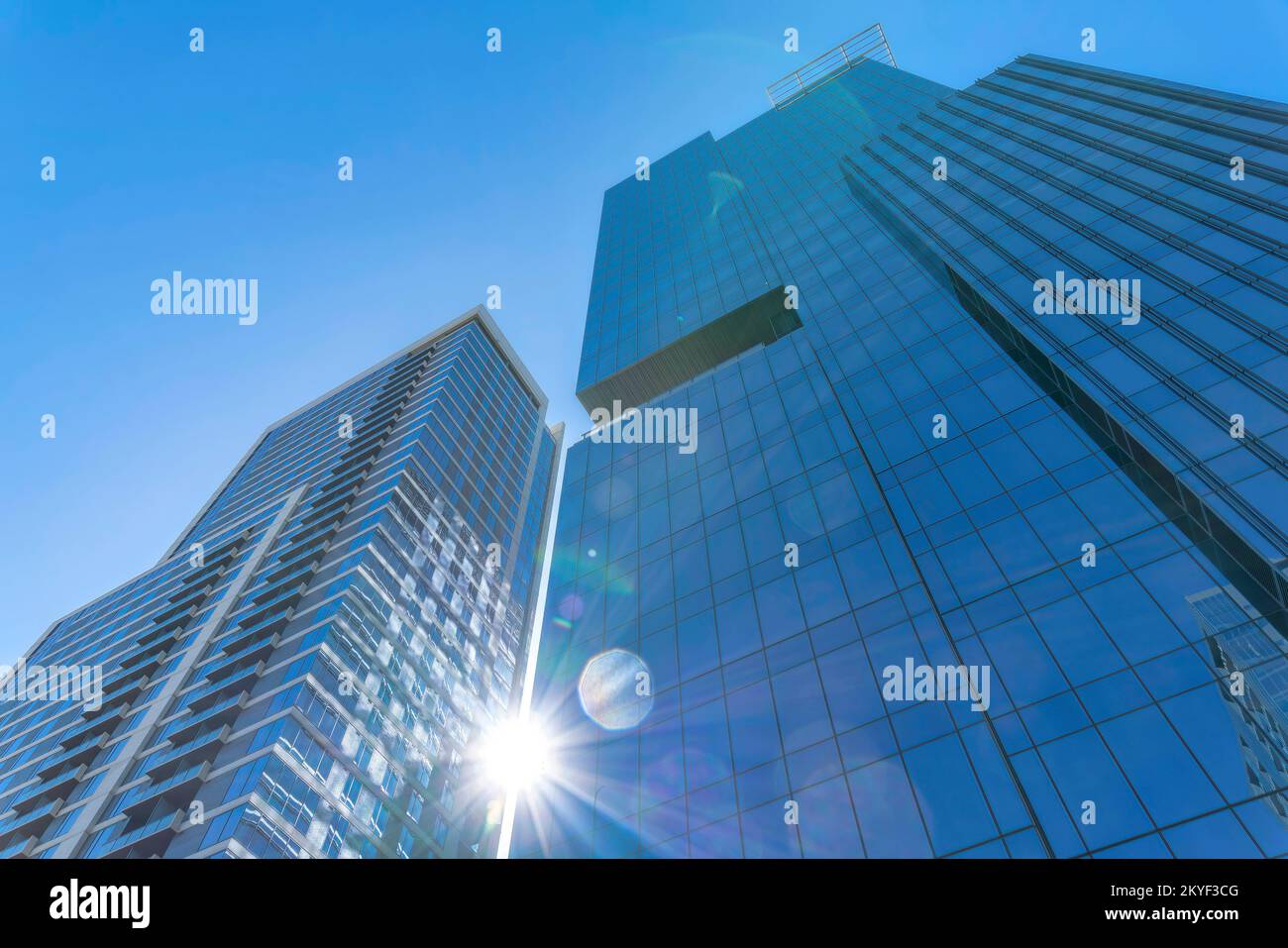 Modern glass residential buildings towering against sun and blue sky ...