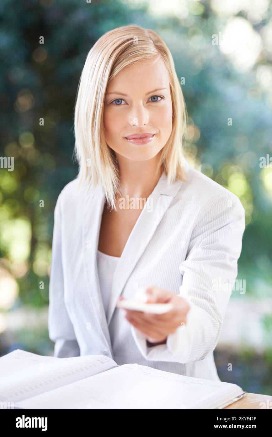 Heres my card. A happy young businesswoman smiling at the camera while ...