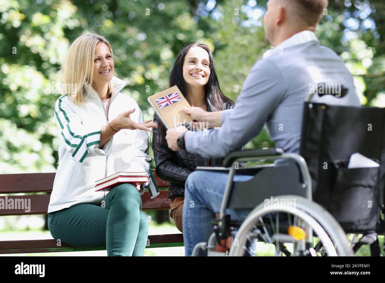 Three friends talk and study outdoors, one disabled person in ...