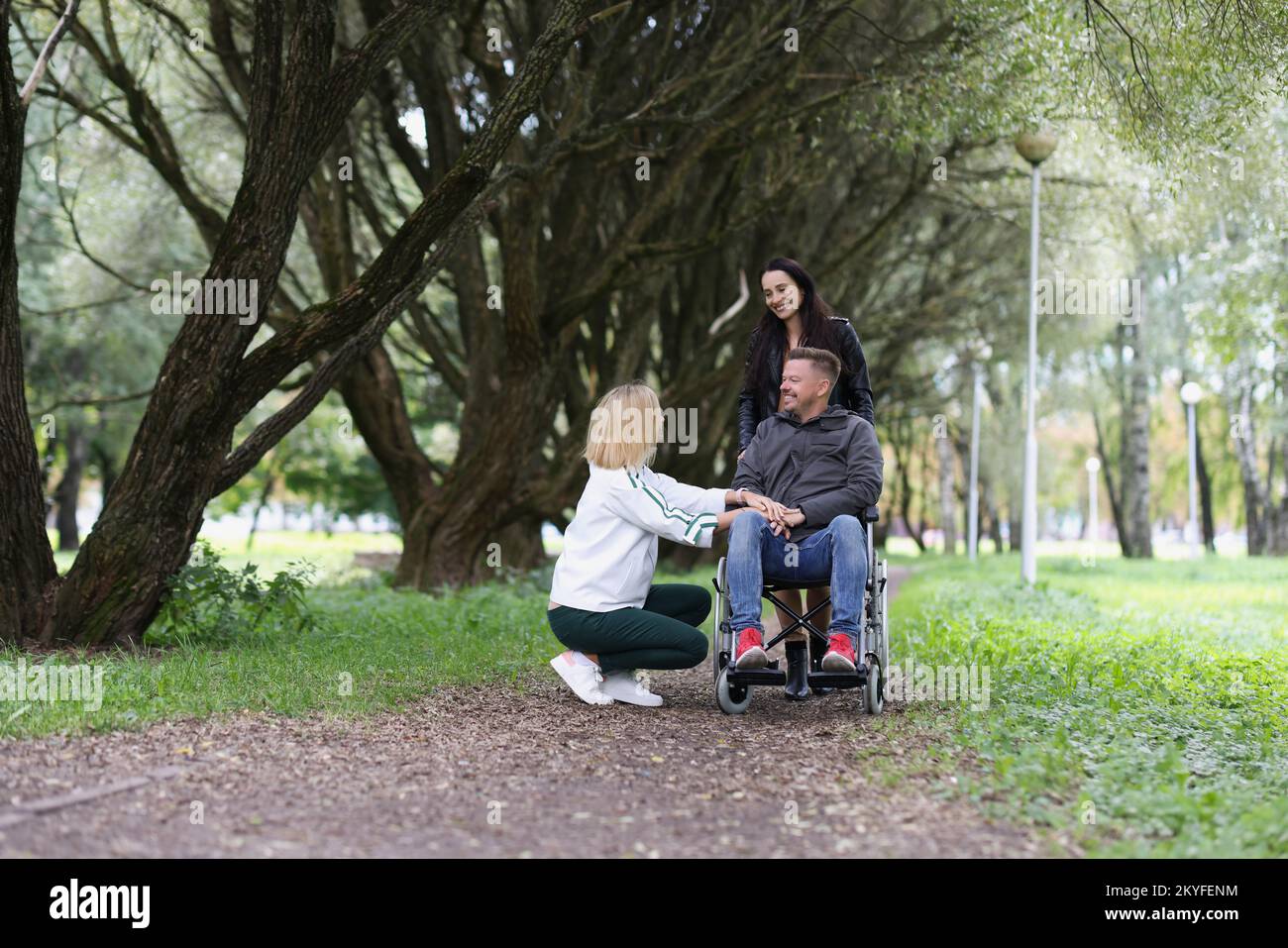 Happy disabled person in wheelchair and two women take care of him in ...