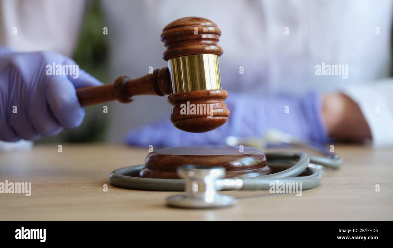 Doctor holds judge gavel in gloved hands close up Stock Photo - Alamy