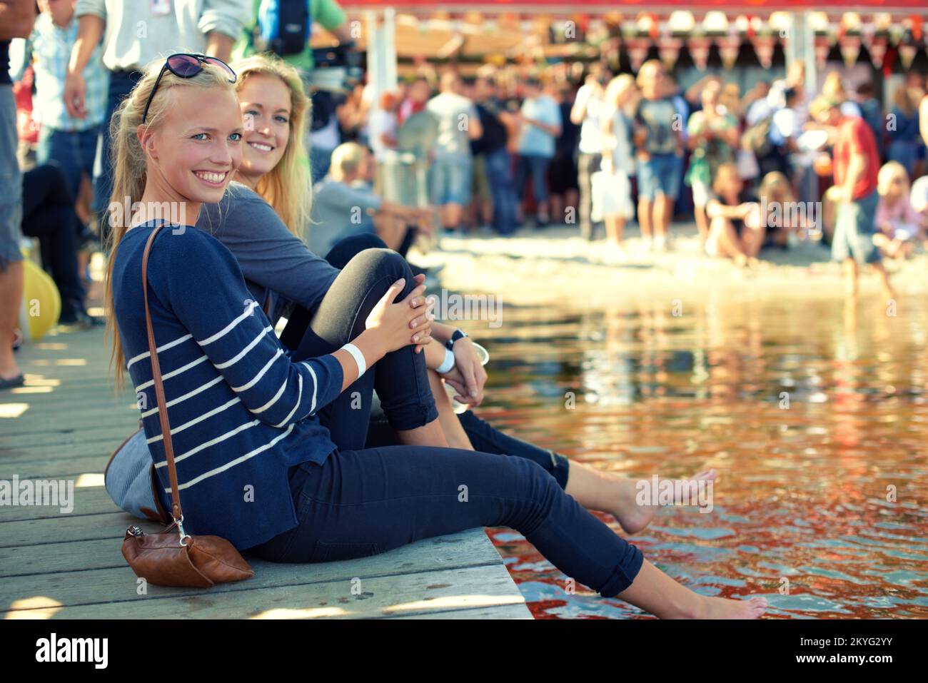 Cooling off. two young women dipping their feet into water at an ...
