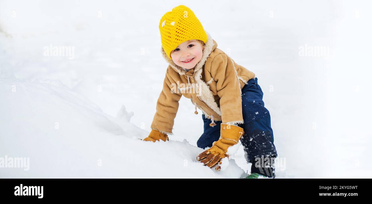 Happy child boy playing wit snow on a winter walk in nature. Happy kid ...