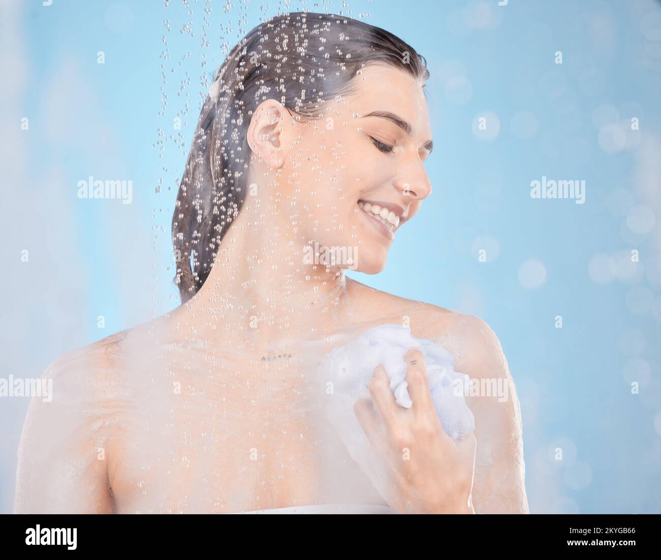 Shower, cleaning and woman with water splash for washing, body care and hygiene on blue ...