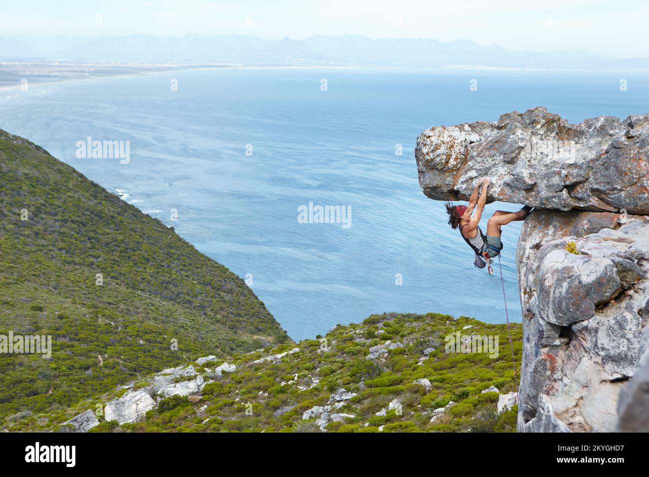Maintaining a strong grip. A young woman rock climbing up the side of a ...