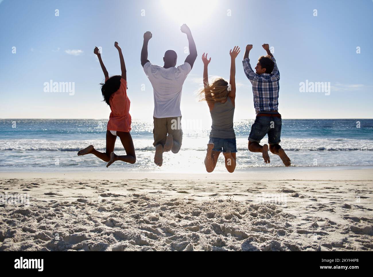 Celebrating summer time. Rear view of two young couple jumping together ...