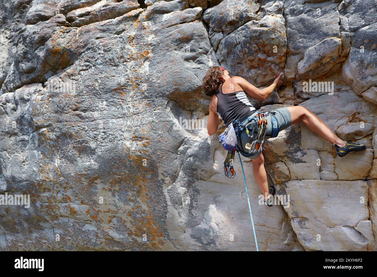 Scaling the rock face. A woman climbing a mountain while secured in a harnas Stock Photo - Alamy