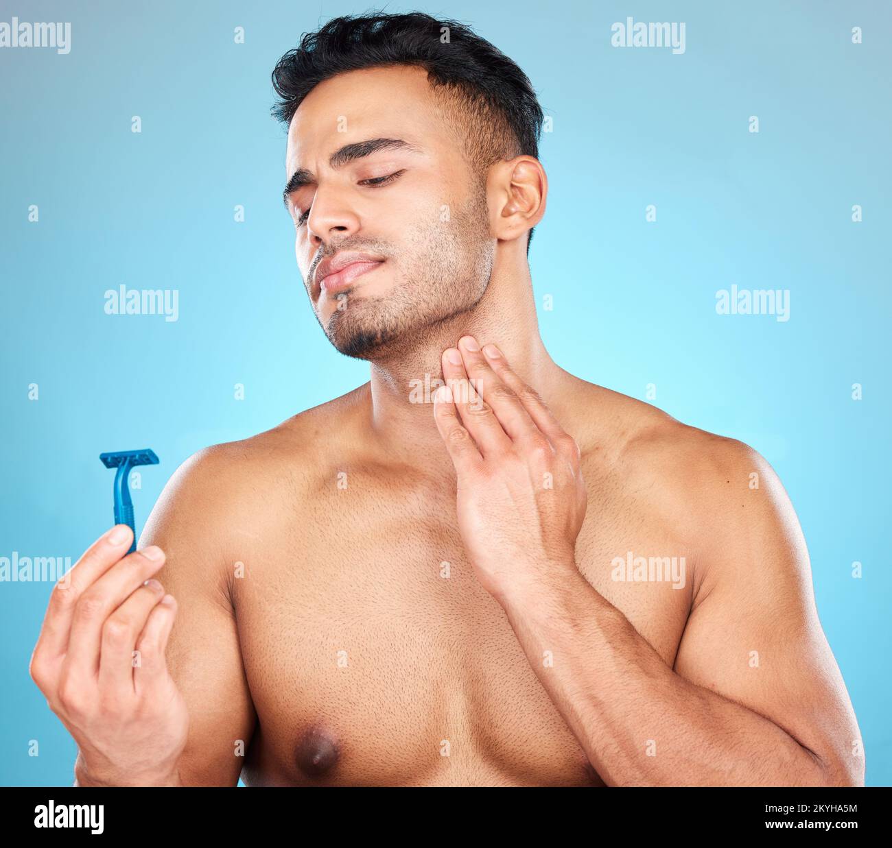 Skincare, shaving and man with razor in studio on blue background for wellness, beauty and self ...