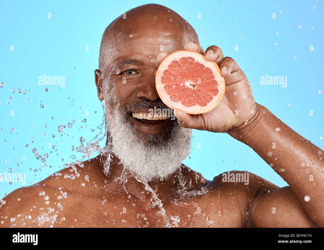 Portrait, skincare or black man with grapefruit studio with water splash on blue background with ...