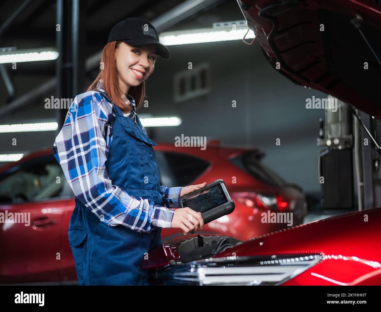 Caucasian female auto mechanic uses a special computer to diagnose ...