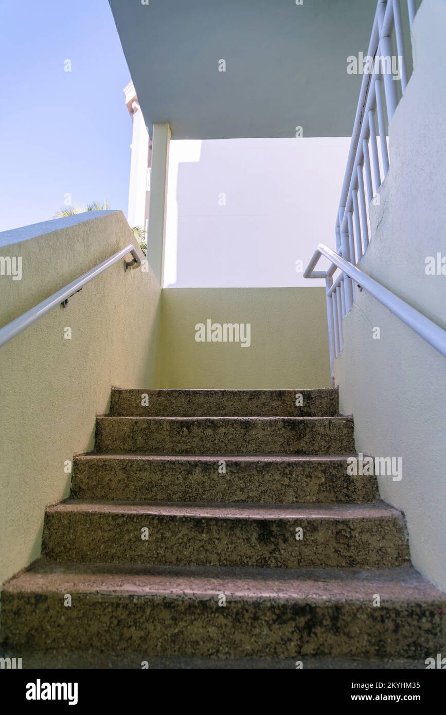 Destin, Florida- Open stairwell in a low angle view. Stairs with granite steps and wall-mounted ...