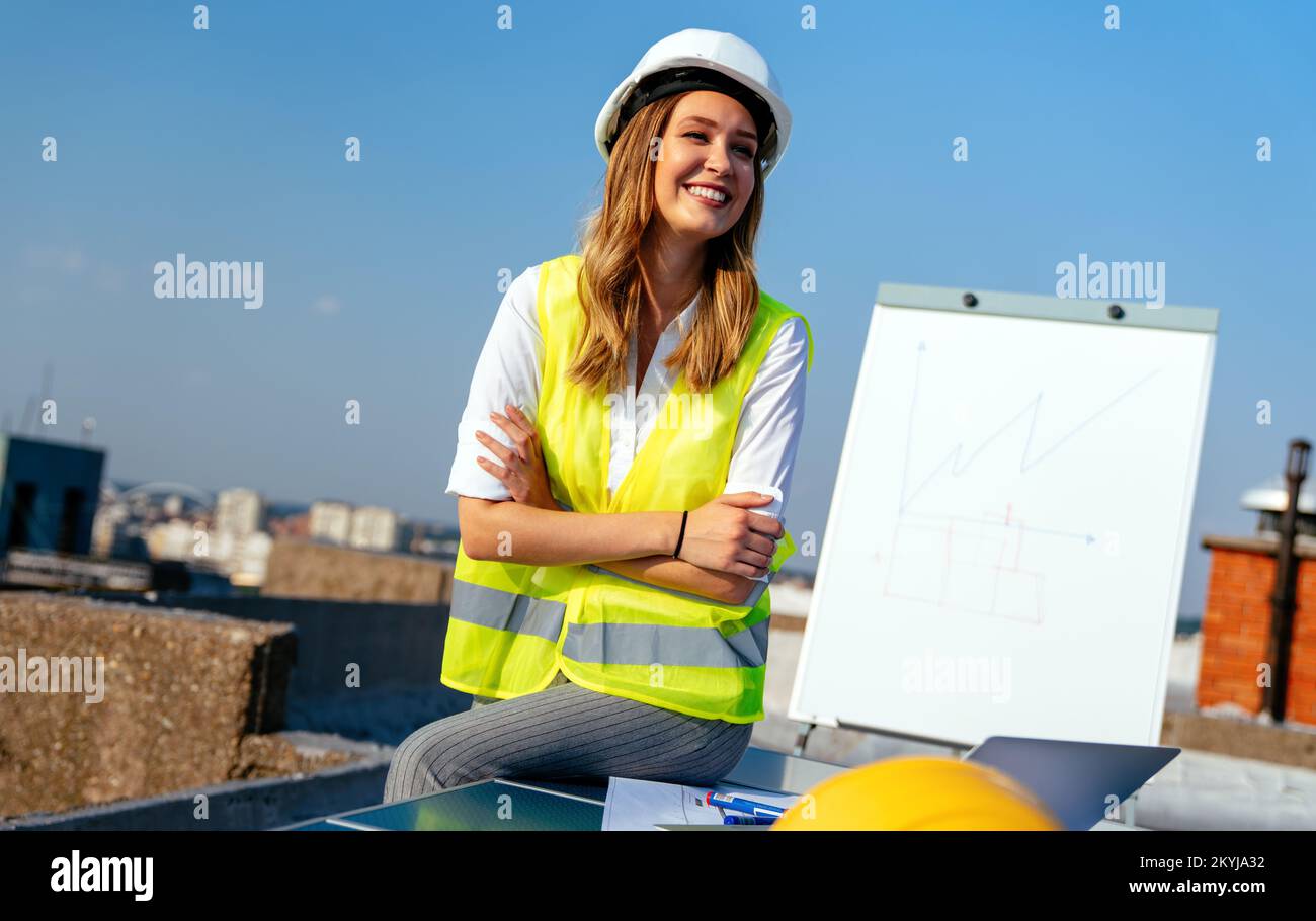 Young female construction specialist engineer reviewing blueprints at ...
