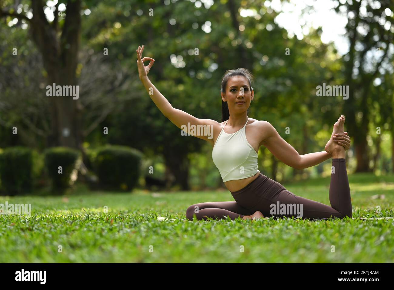 Active millennial woman doing yoga in legged king pigeon pose on green ...