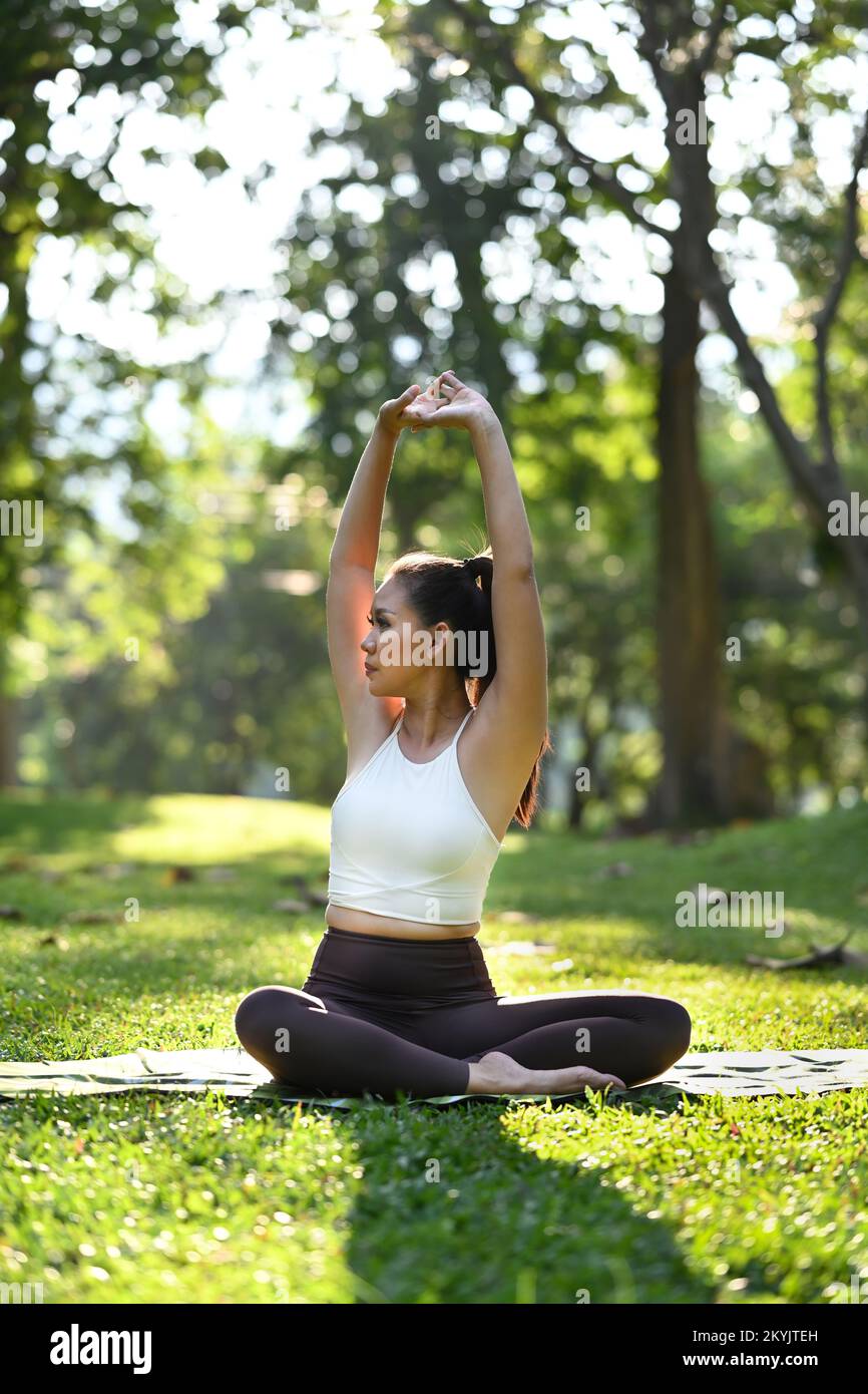 Shot of young woman stretching her arms before practicing yoga lesson outdoors. Fitness, sport ...