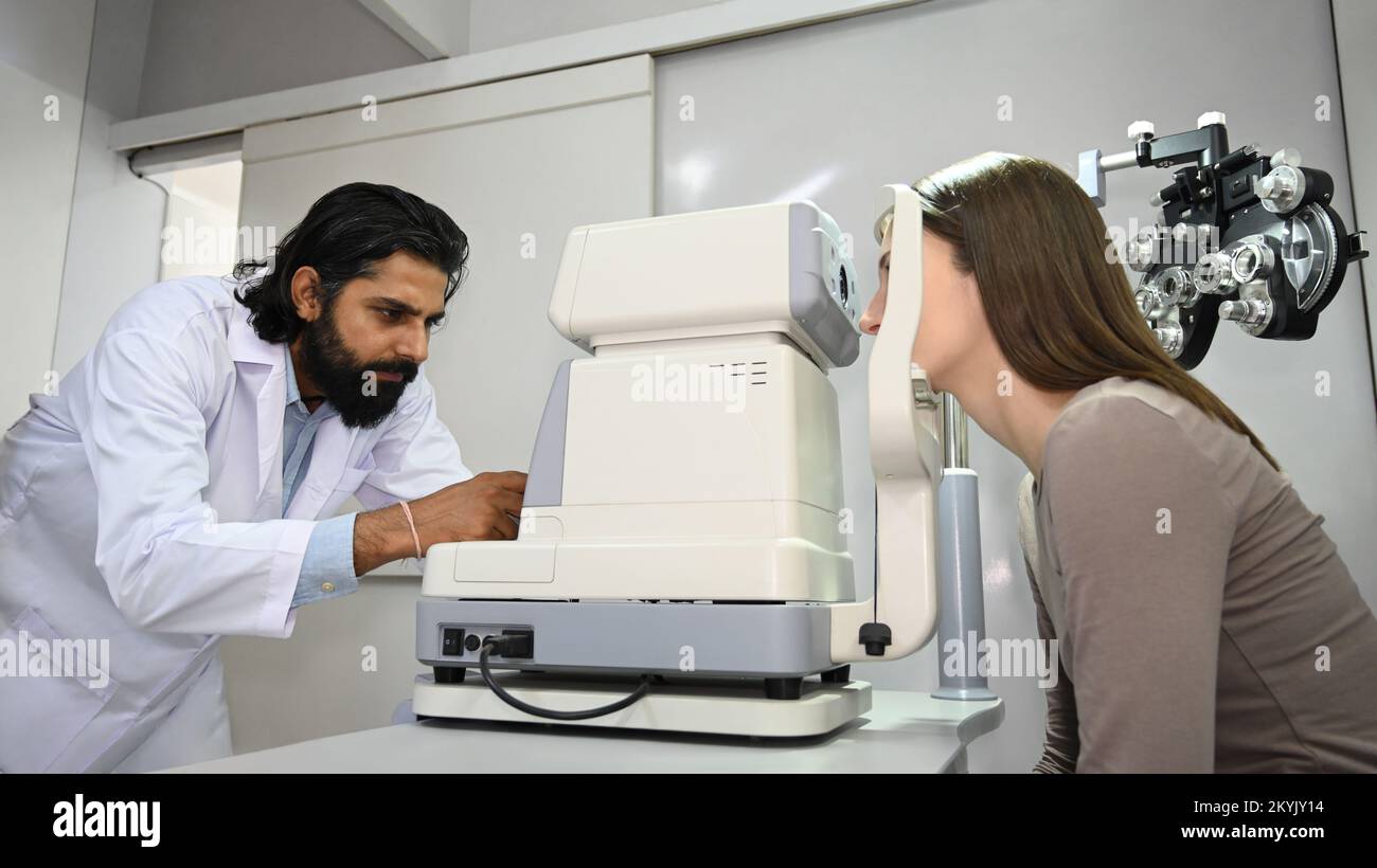 Image of caucasian woman checking eyesight on auto refractor in ...