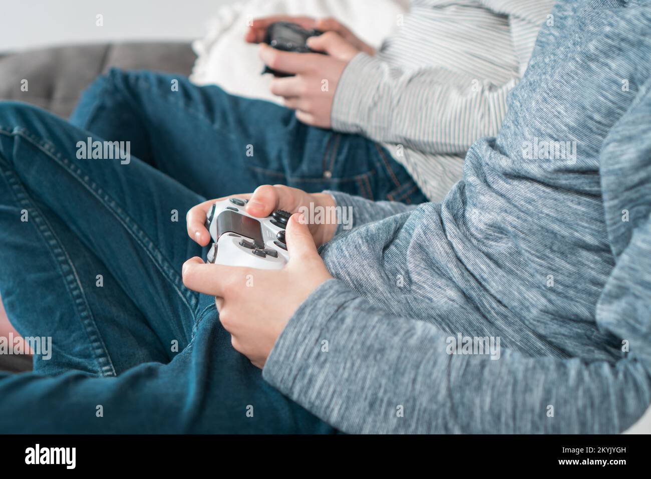 Hands of guys sitting on sofa with game joysticks, closeup side view ...