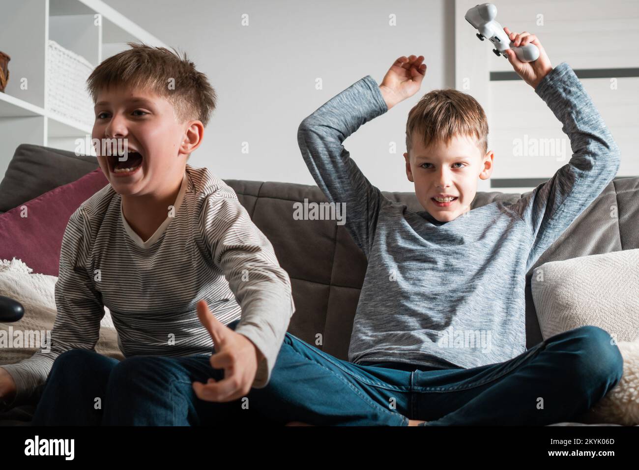 Emotions from winning and losing. School aged boys sit on sofa with ...