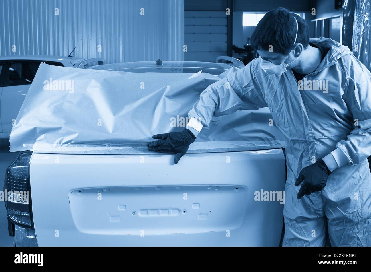Mechanic covering car with paper before painting in auto repair service ...
