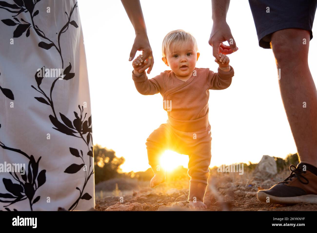 Little girl taking her first steps with the help of her parents Stock ...