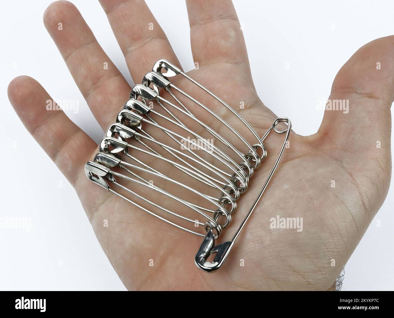 Hand holding safety pins isolated on white background Stock Photo - Alamy