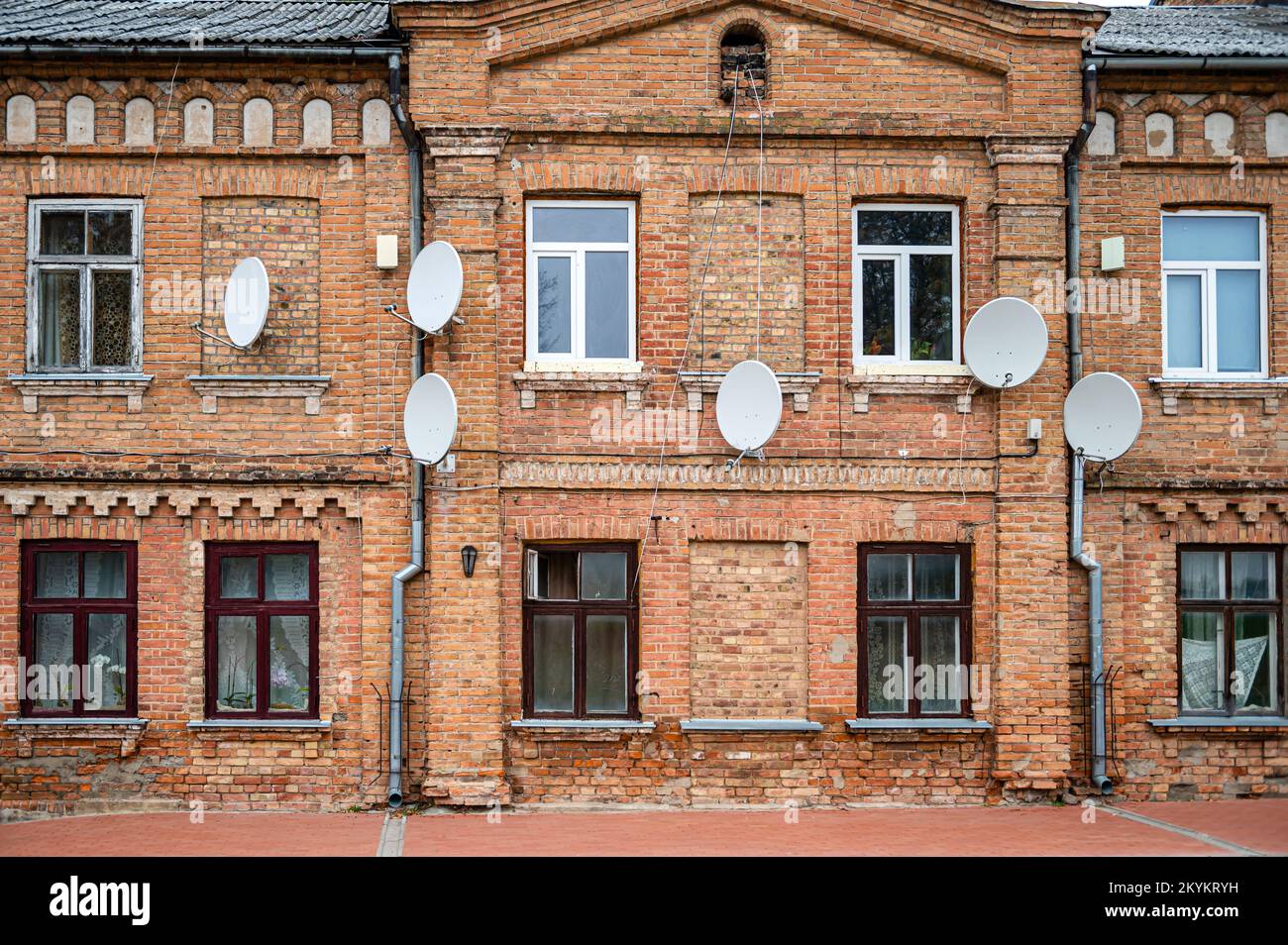 many satellite dishes on the facade of an old red brick building ...