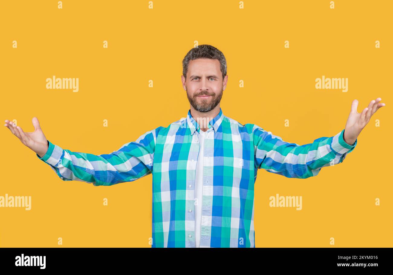 bearded caucasian guy in casual shirt welcoming isolated on yellow ...