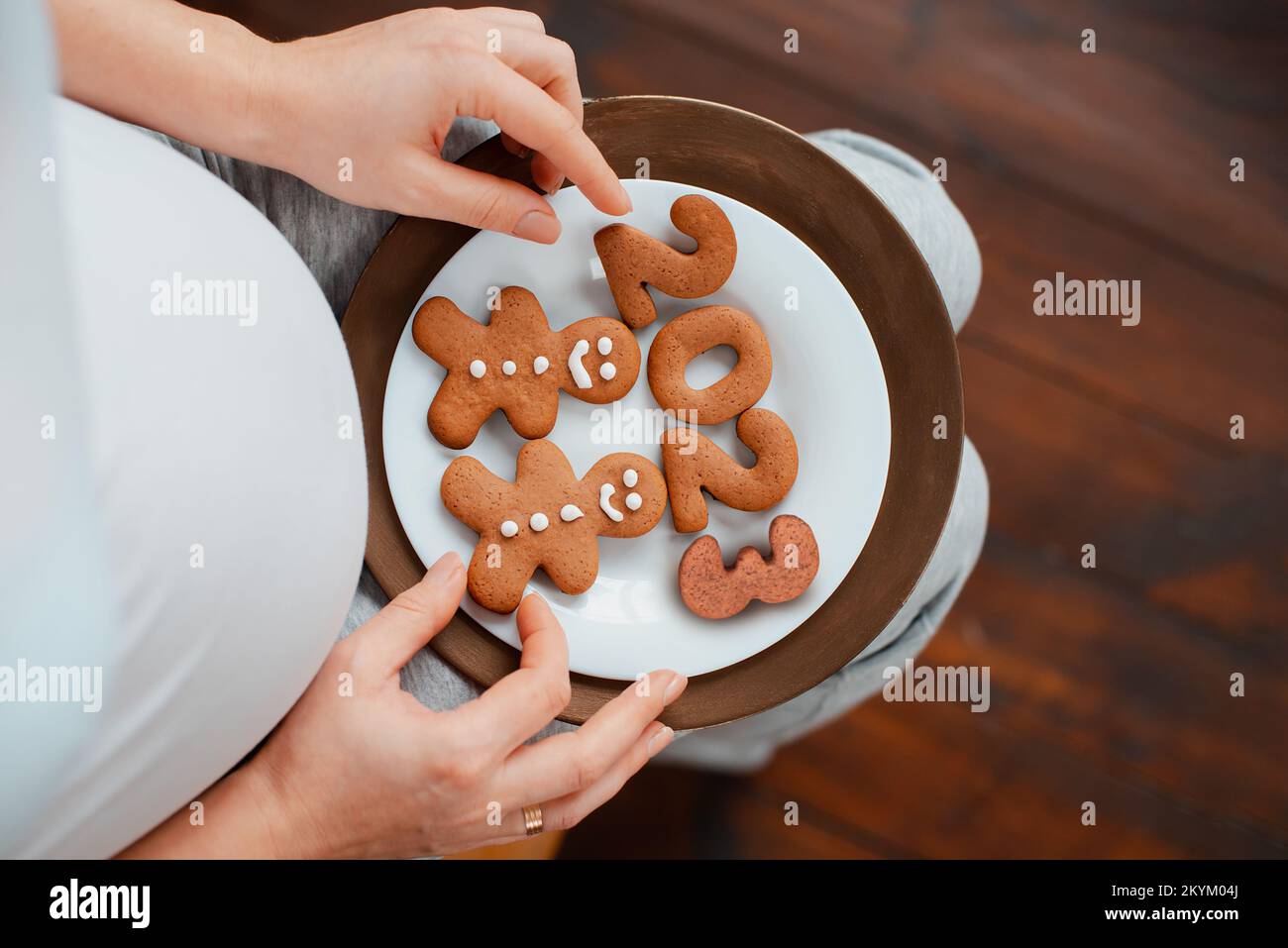 Cropped photo of pregnant woman holding number 2023 of ginger cookies ...