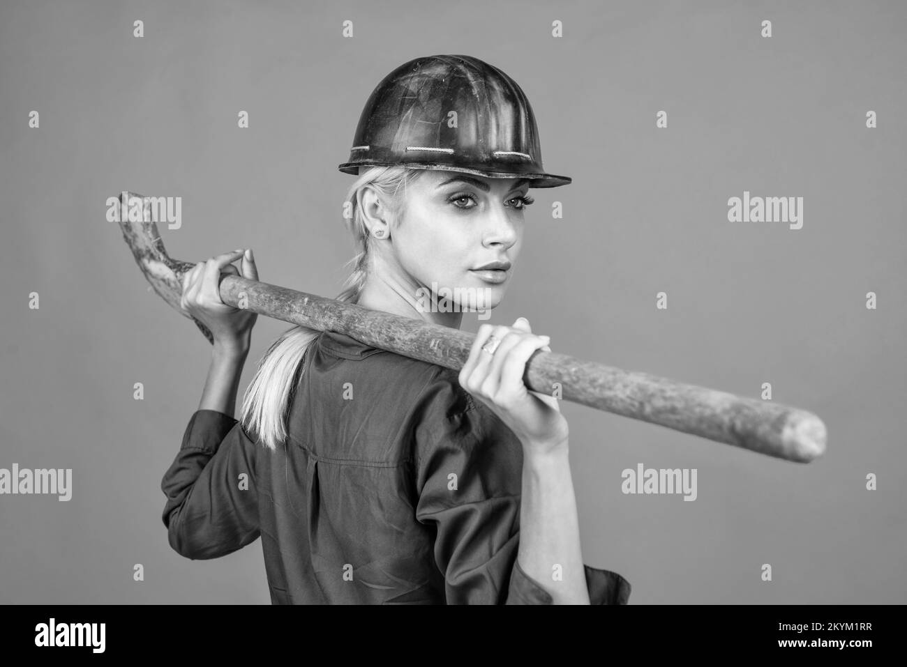 woman architect in protective helmet and boilersuit hold shovel on ...