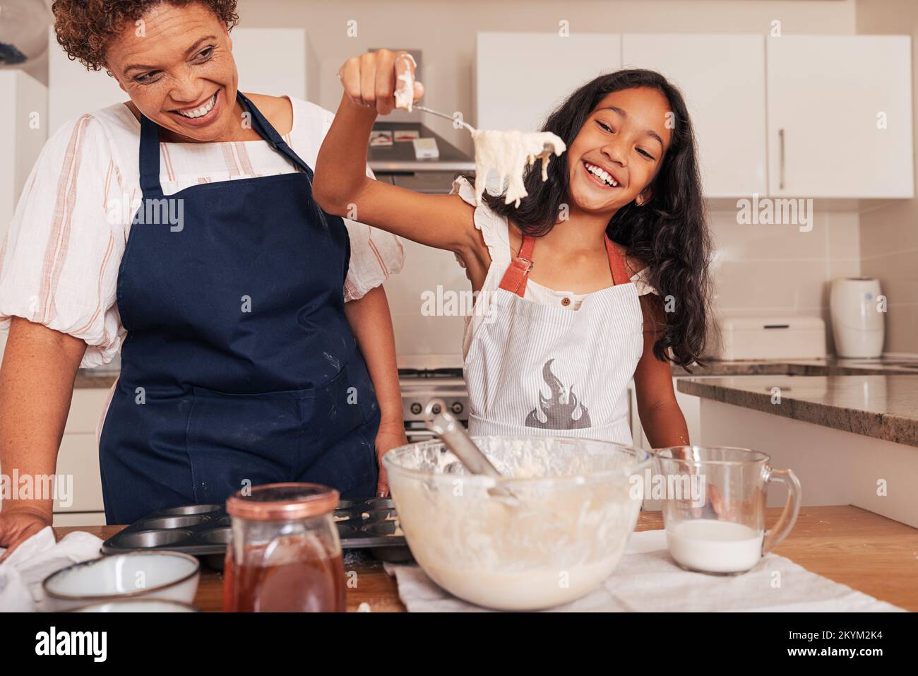 Happy girl scoops batter from a bowl with a spoon Stock Photo - Alamy