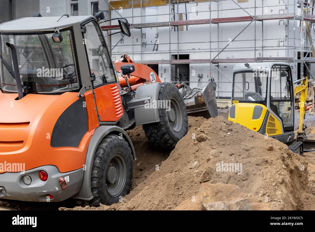 Small loader and excavator digger machine moving heap of earth and ...