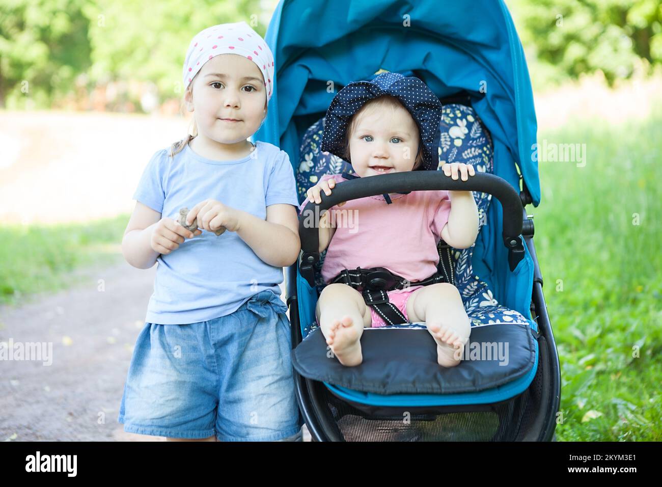Sisters of different ages on a walk in the park, one and three years ...