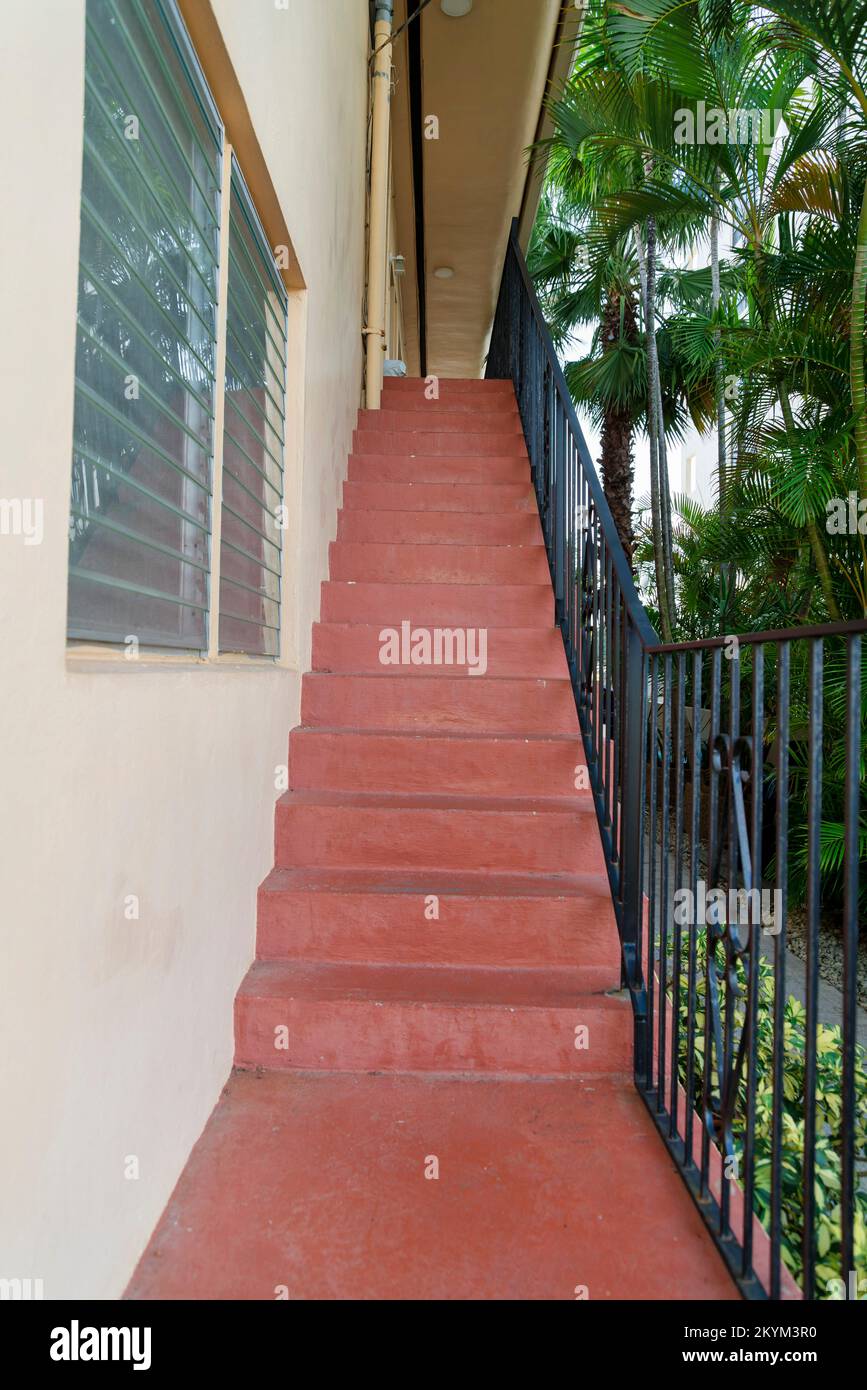 Stairs with red concrete steps and steel railings beside the building ...