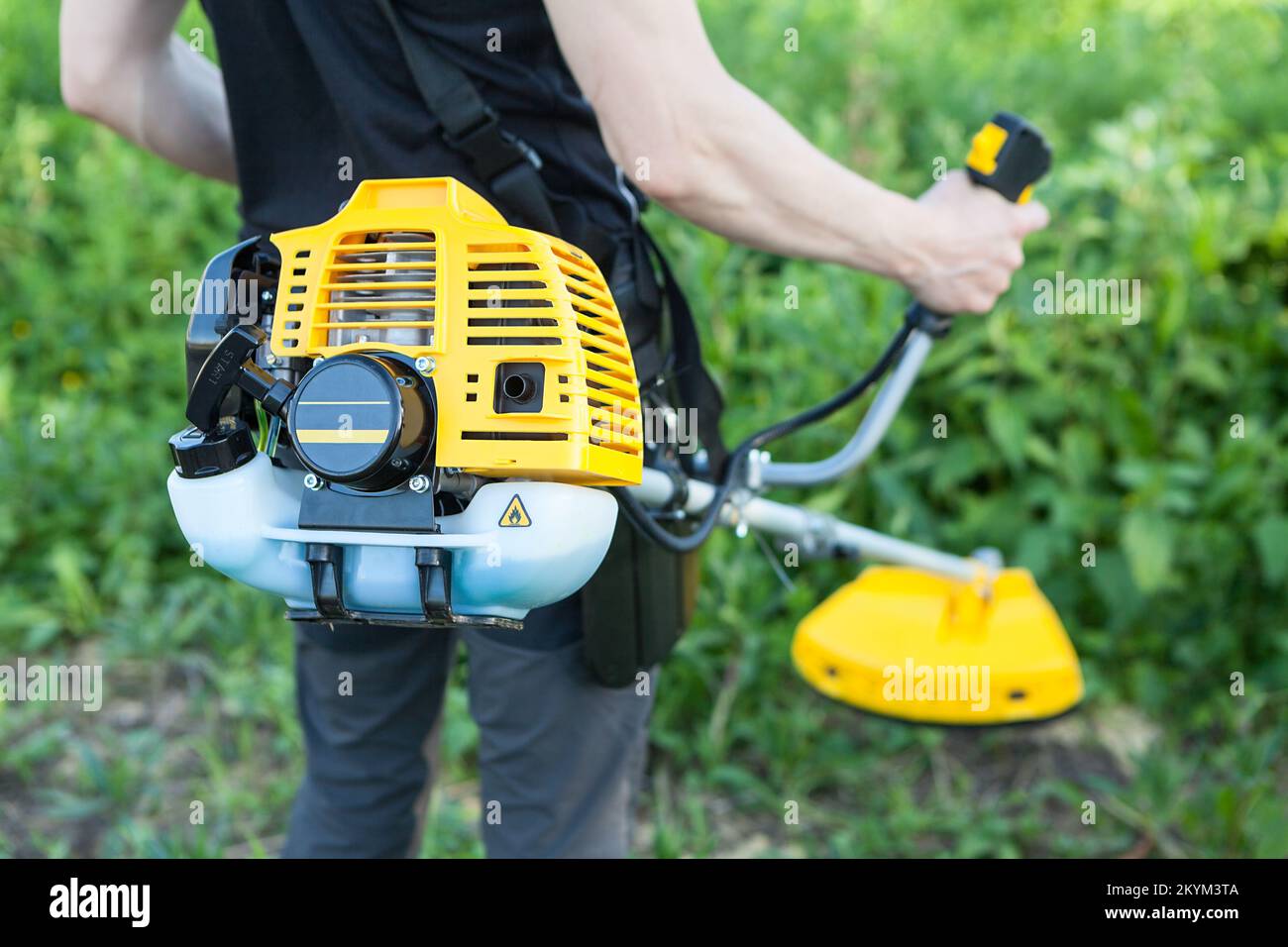 Close-up of a lawn mower with a petrol trimmer in hands, focus is on ...
