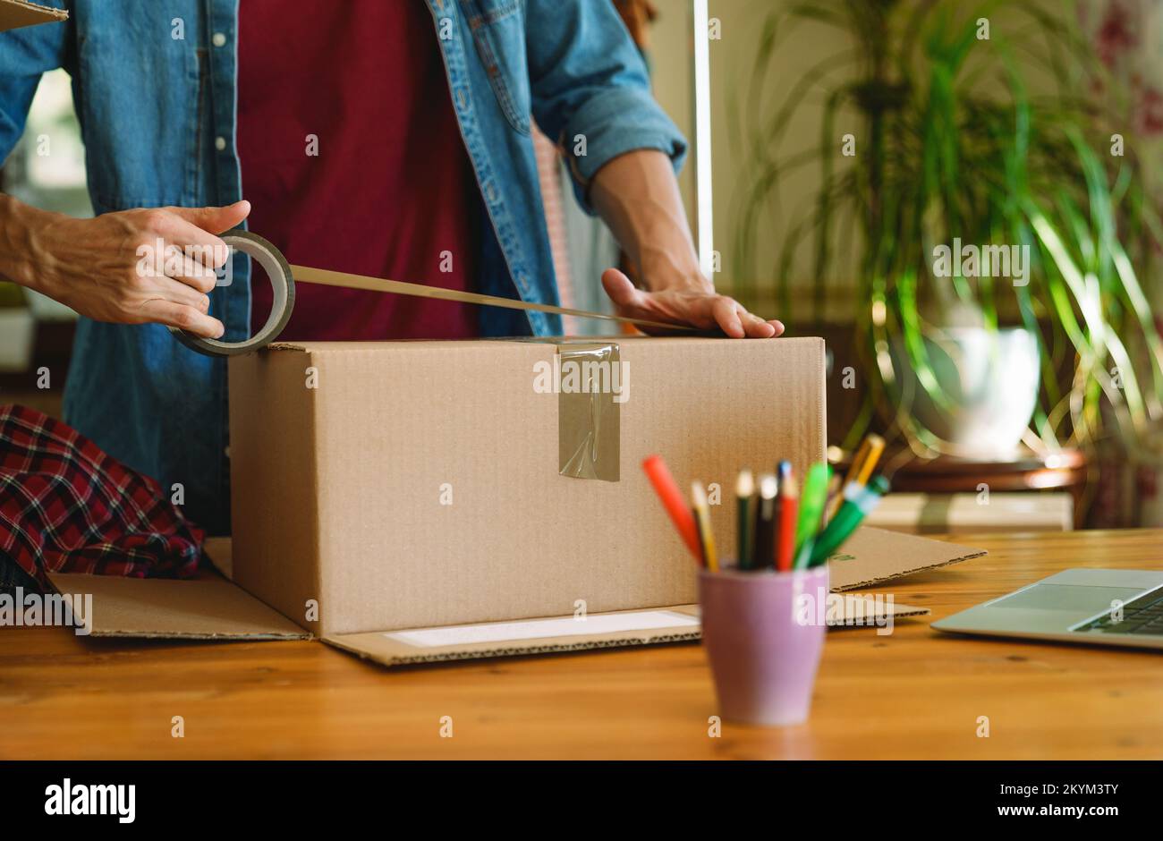 Man sealing parcel with duct tape Stock Photo - Alamy