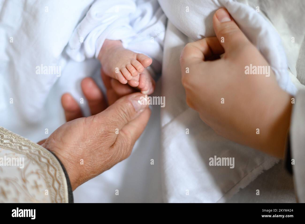 The sacrament of baptism of a baby in the church, the baby's legs on a ...