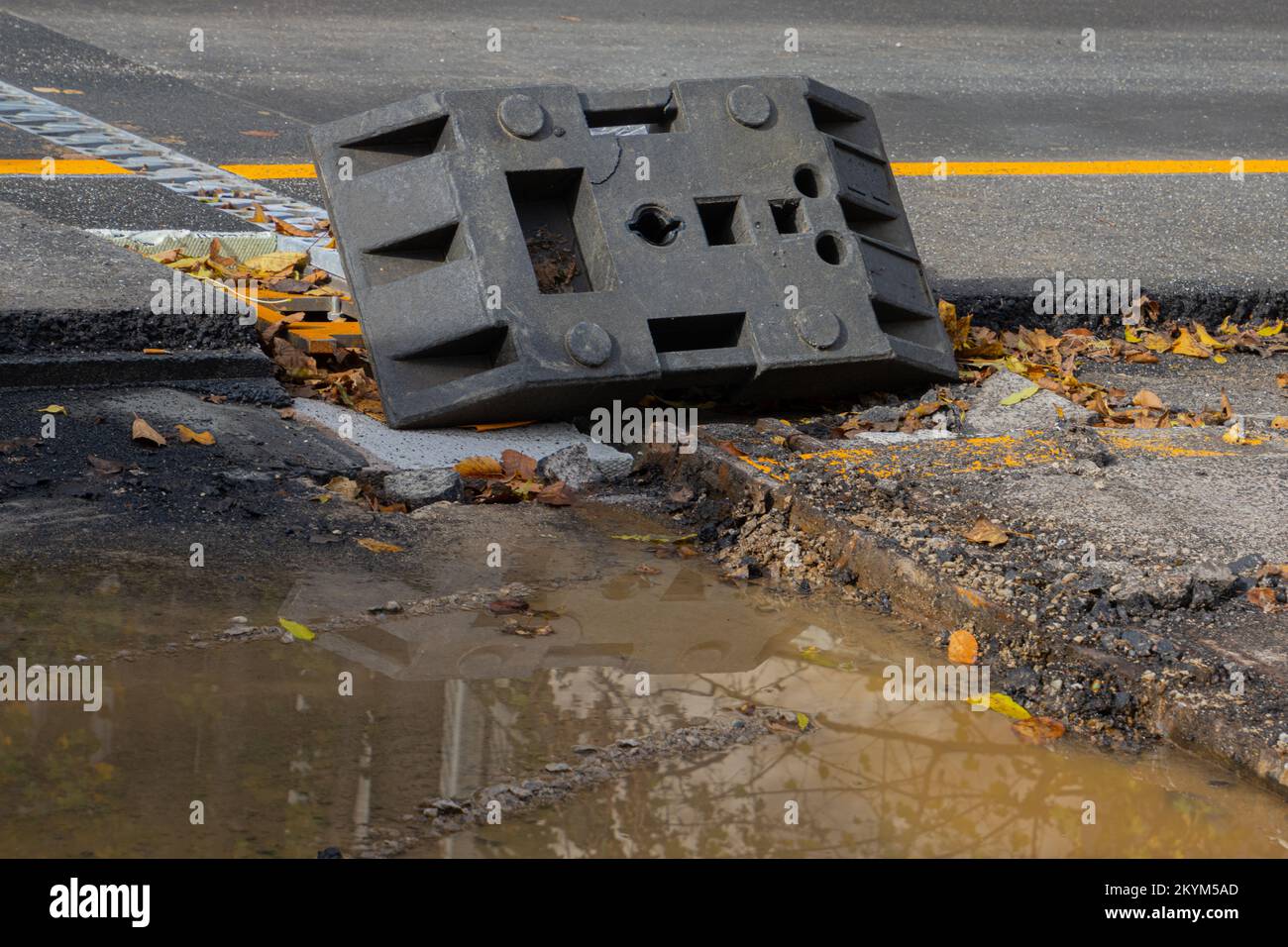 Edge of milled asphalt road patch and a water puddle at a construction ...