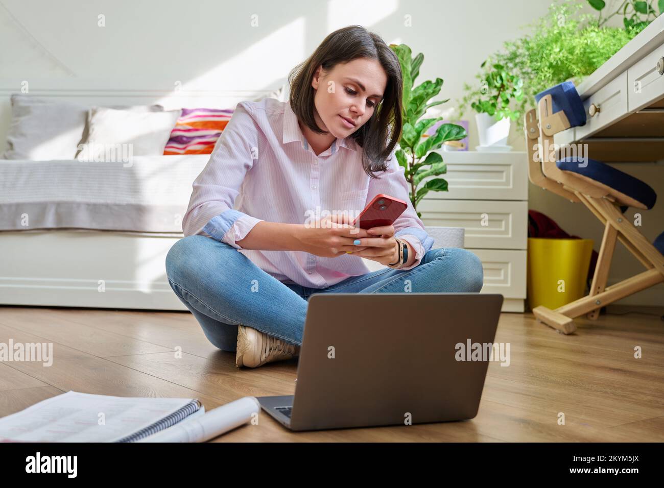 Young female university student studying at home sitting on floor using ...