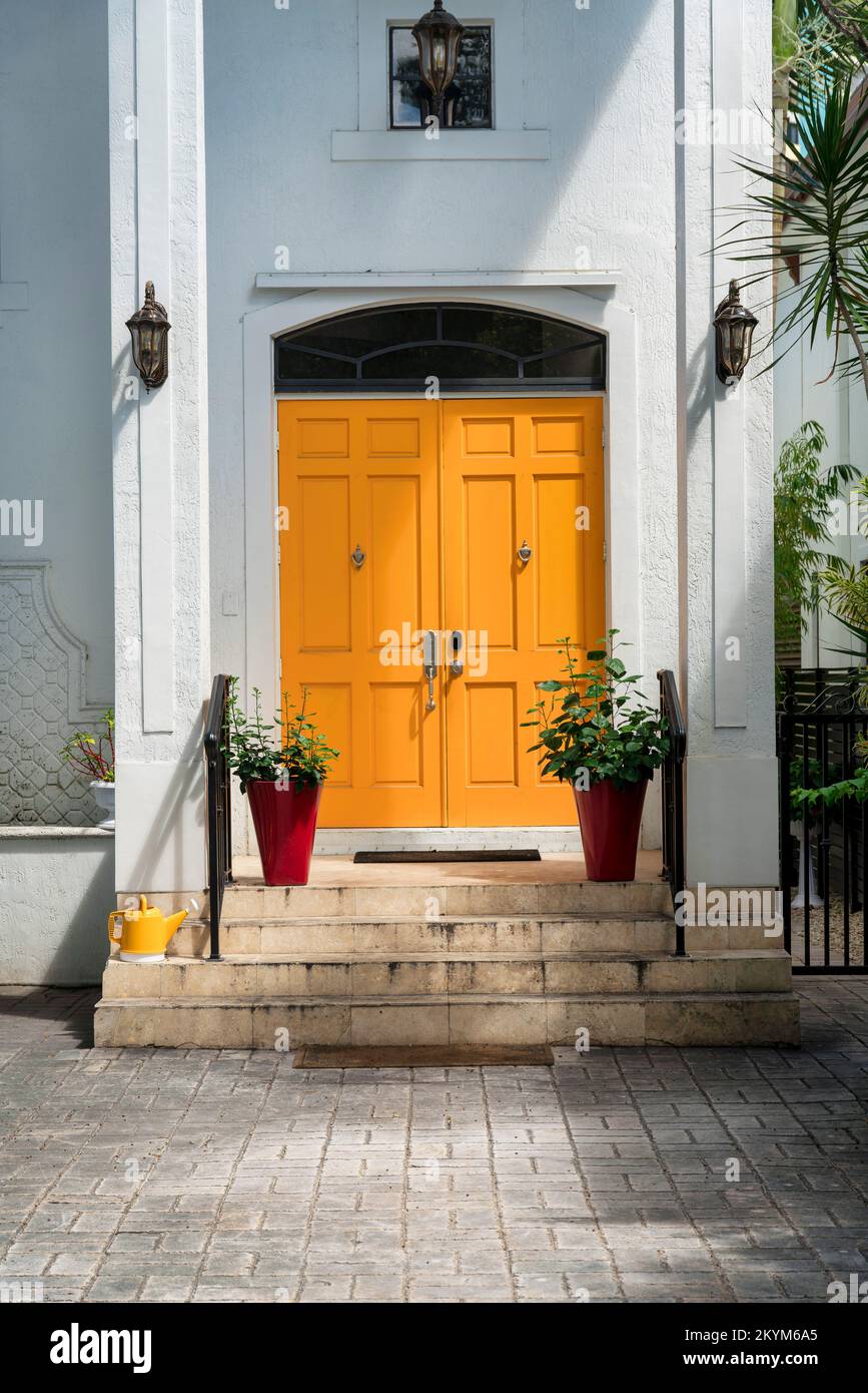 Orange double front doors with arched transom window and potted plants ...