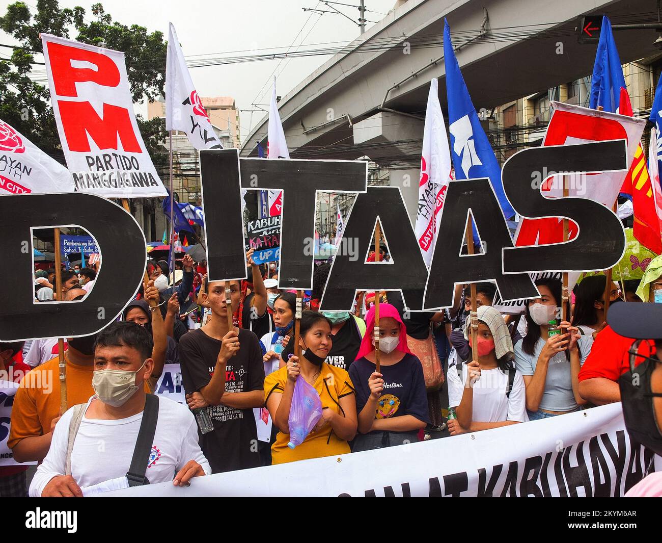 Protesters hold signs and a banner on Bonifacio Day calling for higher ...