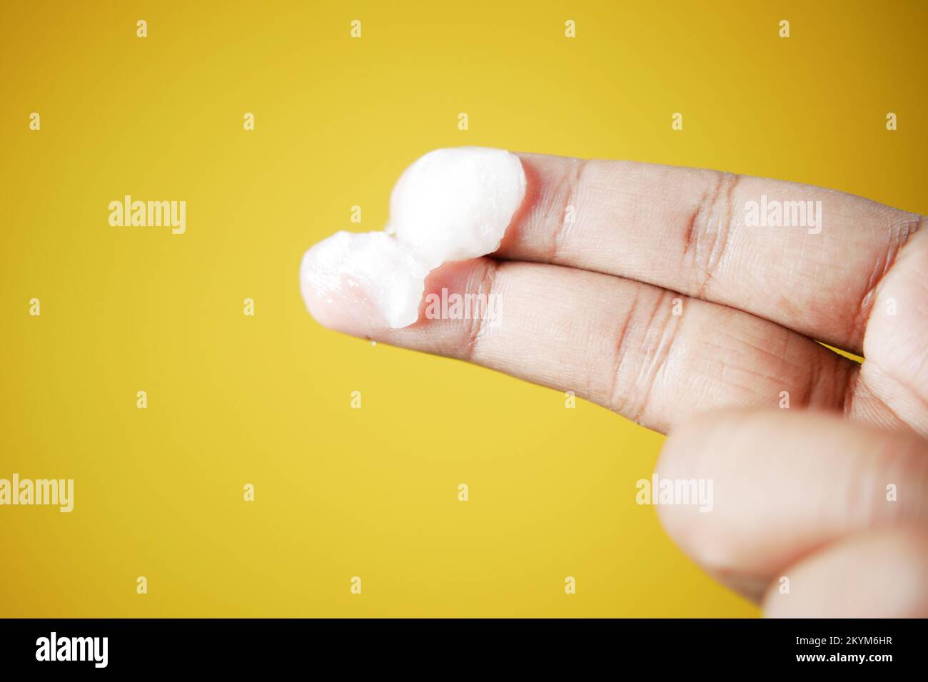 Close up of man hand using petroleum jelly against yellow background ...