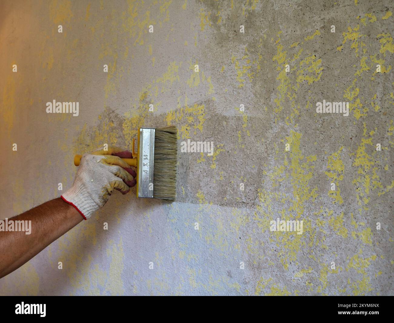 a hand with a brush applies a layer of glue or primer on a textured ...